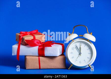 Alarm clock and stack of Christmas gifts on snow against grunge ...