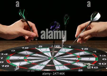 People taking darts out of dartboard Stock Photo - Alamy