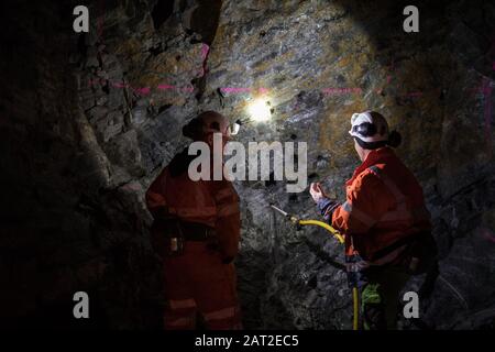 Drilling in an underground gold mine showing high pressure hoses and ...