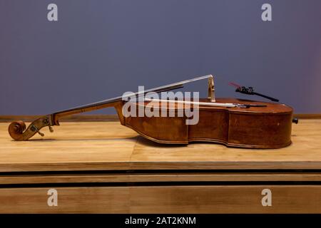 An old broken double bass lying on a wooden table on the background of ...
