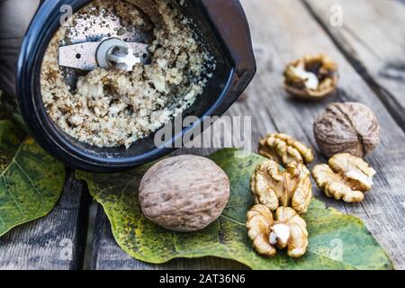 chopped walnut in a coffee grinder near the walnut kernel on an old ...