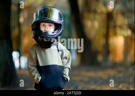 funny kid with a big motorcycle helmet on his head. Helmet boy Stock ...