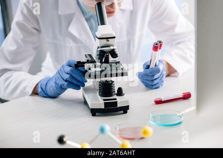 cropped view of genetic consultant holding test tubes and using ...
