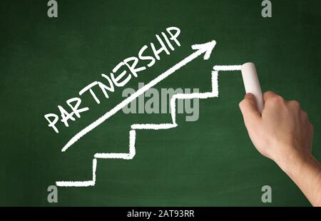 Hand drawing PARTNERSHIP inscription with white chalk on blackboard ...