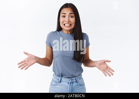 Oops sorry. Apologizing asian girl spread hands sideways, shrugging ...