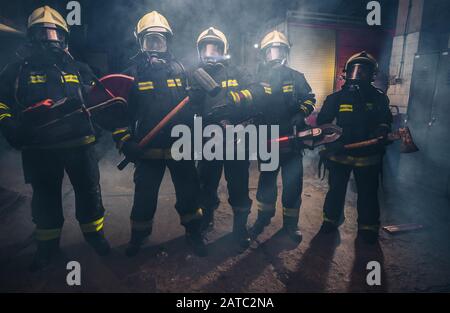 Group of firefighters with chainsaw and sledge hammer practicing in the ...