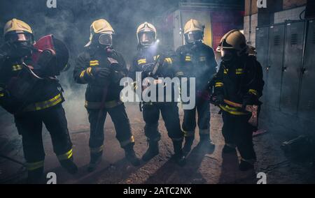 Group of firefighters with chainsaw and sledge hammer practicing in the ...