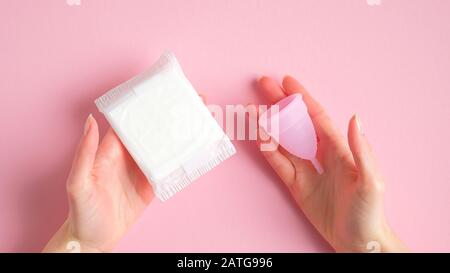Female hands with reusable menstrual pad and flower on color background ...