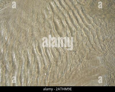 Water flowing over sand forming pattern Stock Photo - Alamy