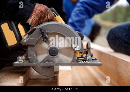 Worker uses circular saw to cut wooden beams in backyard during ...