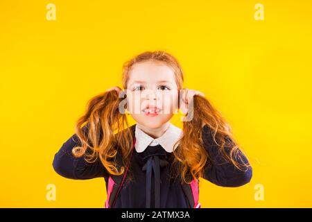 Pretty schoolgirl with two tails wears school uniform over yellow ...
