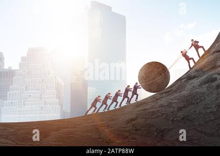 Team of people pushing stone uphill Stock Photo - Alamy