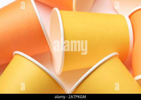 Orange and yellow paper party cups on a white and green background ...