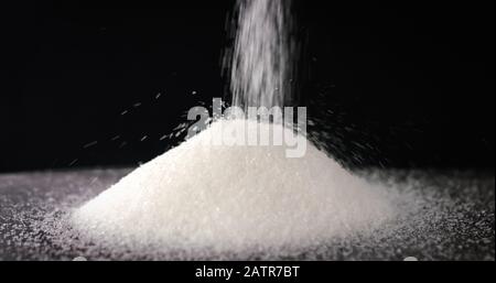 white sugar and table salt in clay bowls isolated on black background ...