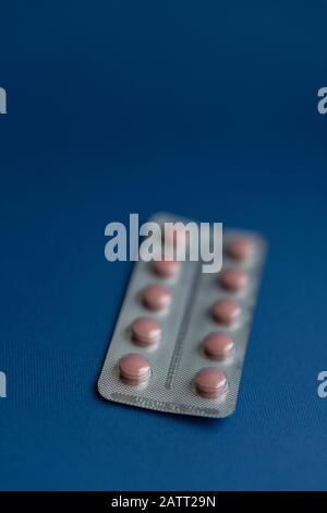 Heap of pink and blue pills on colored background. Tablets scattered on ...