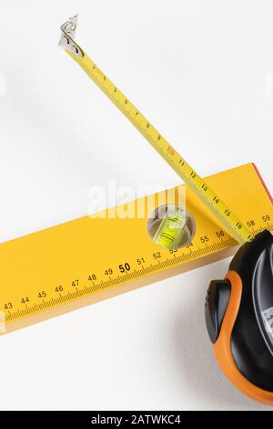 Yellow tape measure spirit level and wing nuts on clear white ...