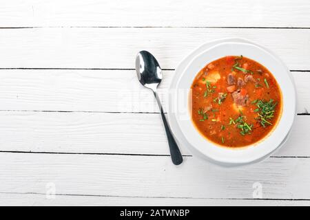 Soup with beef tomatoes and fresh vegetables. On a wooden background ...