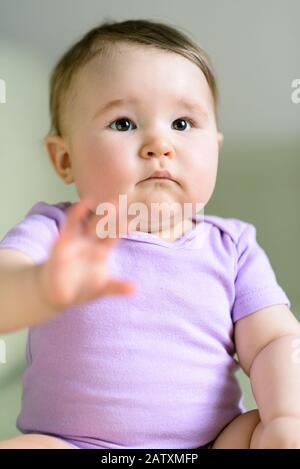Cute little girl raising hand in classroom Stock Photo - Alamy