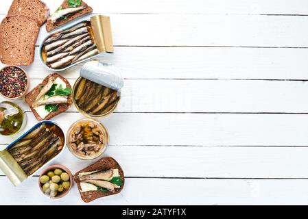 Sprats with oil in a jar. On a white wooden background. top view. Free ...