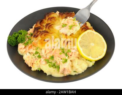 Portion of crispy potato topped fish pie on a black plate isolated on a ...