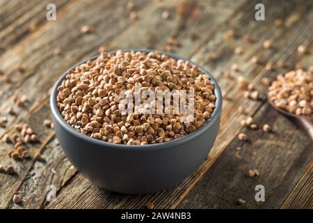 Bowl of dry raw buckwheat groats and wooden scoop on a wooden ...