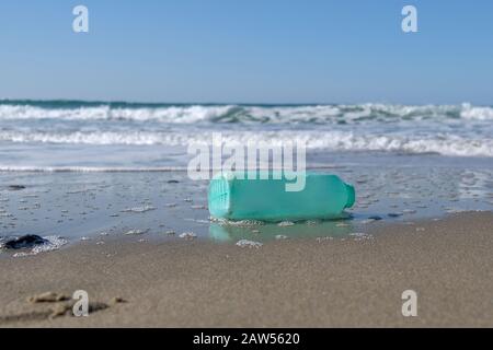 Plastic soap container on wild sea coast polluted ecosystem, industrial ...