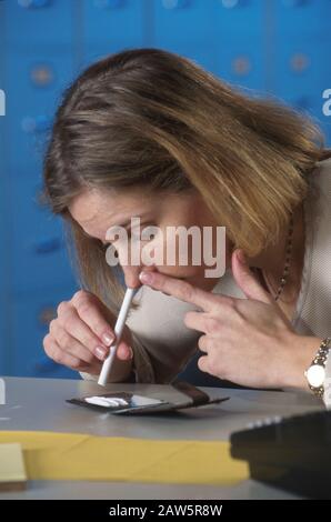 Drug addict woman snorting cocaine powder with rolled dollar banknote ...