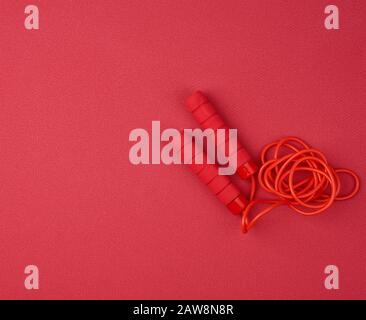 red jump rope lies on a neoprene red sports mat, close up, copy space ...