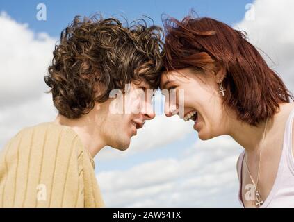 Teenage couple with heads together smiling Stock Photo - Alamy