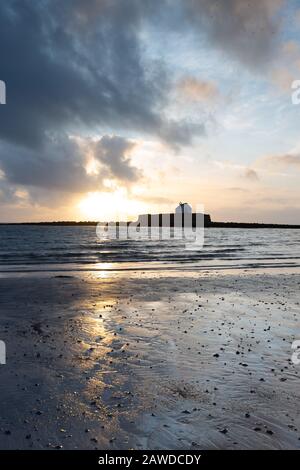View of St Cwyfan's Church on Cribinau island surrounded by a stone sea ...