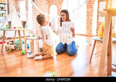 Beautiful psiychologist and toddler doing therapy around lots of toys ...
