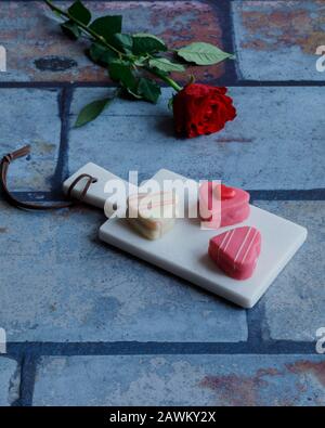 Tasty heart-shaped candy and flowers on white background Stock Photo ...