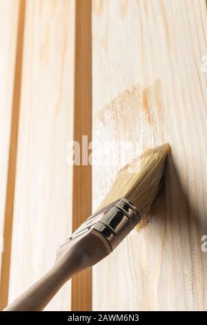Carpenter brushing varnish on wood to build up protective layer with ...