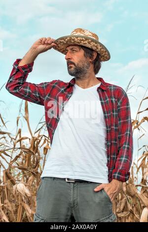Farm worker wearing red plaid shirt and trucker's hat standing in ...