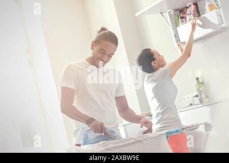 Couple ironing clothes at laundry room smiling happy pointing with hand ...