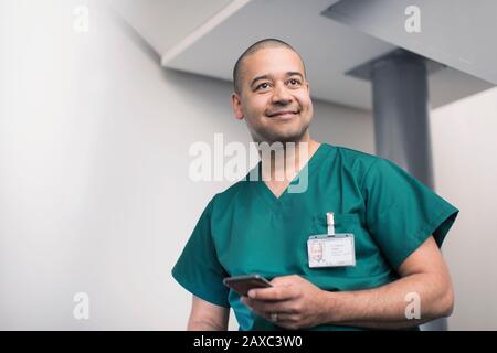 Smiling male surgeon using mobile phone Stock Photo - Alamy