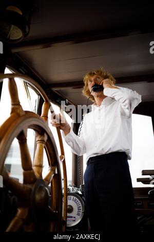 Sail boat captain behind the steering wheel of his vessel. Sailboat ...