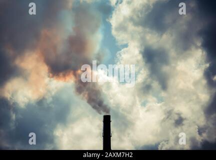 pipe with thick smoke and the sky on contrasting background of clouds ...