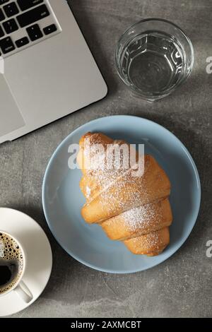 Composition with croissant and computer on grey background, top view ...