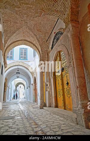 Typical cobbled and narrow street with columns and arcades inside the ...