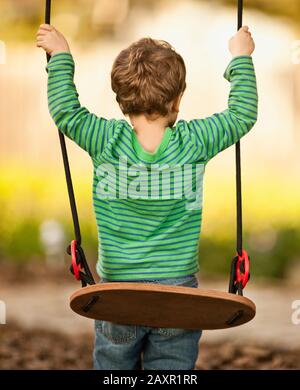 Toddler plays on rope swing with his mother or babysitter. Physical ...