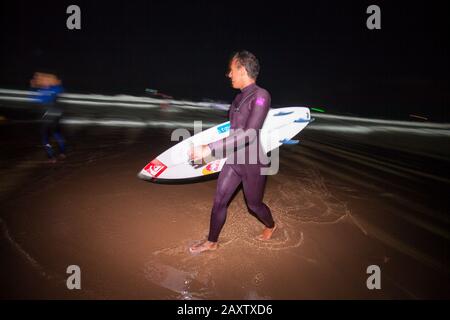 Surfers going surfing at night with neon surfboards Stock Photo - Alamy