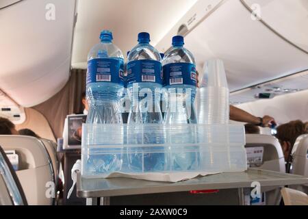 Member of cabin crew with water drinks trolley delivers refreshments to ...