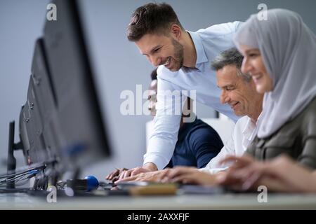 Manager Helping Staff In Busy Office Environment Stock Photo - Alamy