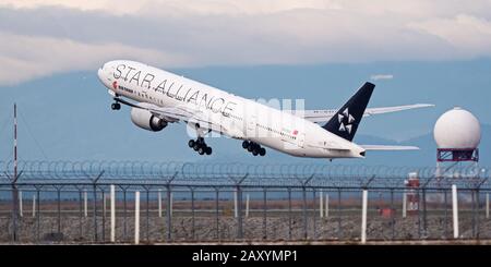 A Star Alliance airplane takes off in front of other planes parked at ...