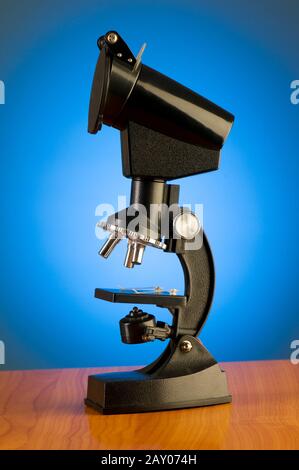 Microscope against blue gradient background Stock Photo - Alamy