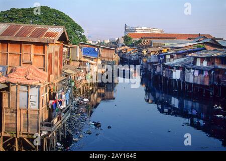 Riverside slum homes made up of shacks along a canal strewn with ...
