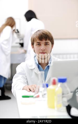 Young male scientist working with female colleague in chemical ...