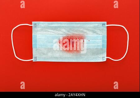 Hemoptysis, coronavirus, protective surgical mask with blood on red ...