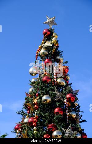 Silver, gold, and red baubles and string lights decorate a Christmas ...